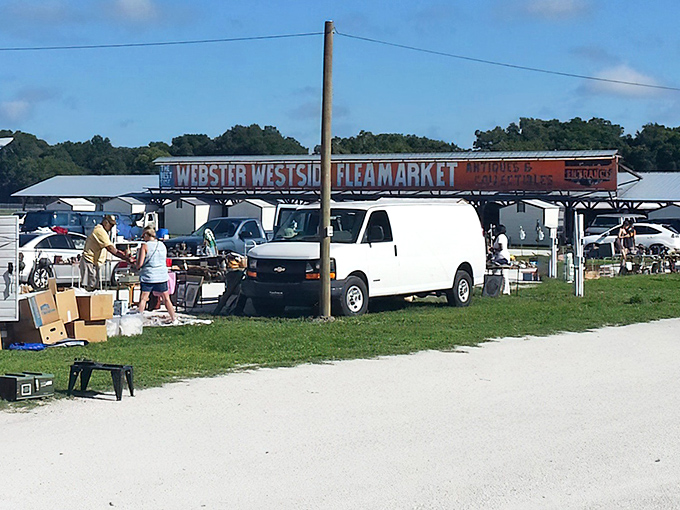 The gateway to bargain paradise! Webster Westside Flea Market's iconic entrance sign welcomes treasure hunters while vendors set up shop in the background.