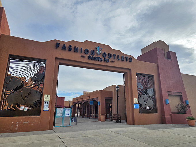 The iconic terracotta entrance to Fashion Outlets of Santa Fe stands like a Southwest welcome committee, promising retail therapy under that famous New Mexico blue sky.