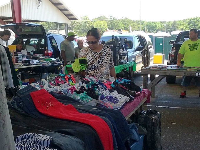 The art of the browse in full swing! A shopper carefully examines colorful clothing at a vendor's table, where yesterday's fashion finds new life and $40 might score an entire wardrobe refresh.