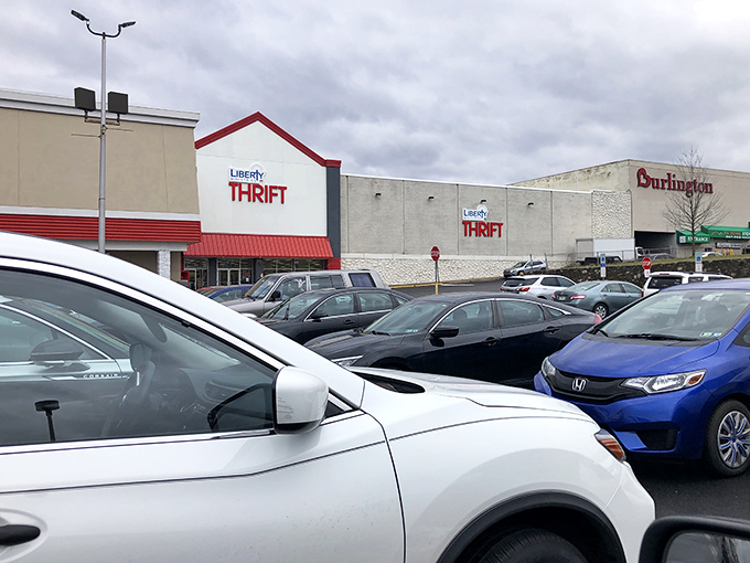 The distinctive red-trimmed facade of Liberty Ministries Thrift stands like a beacon for bargain hunters. Even the parking lot hints at the treasures waiting inside.