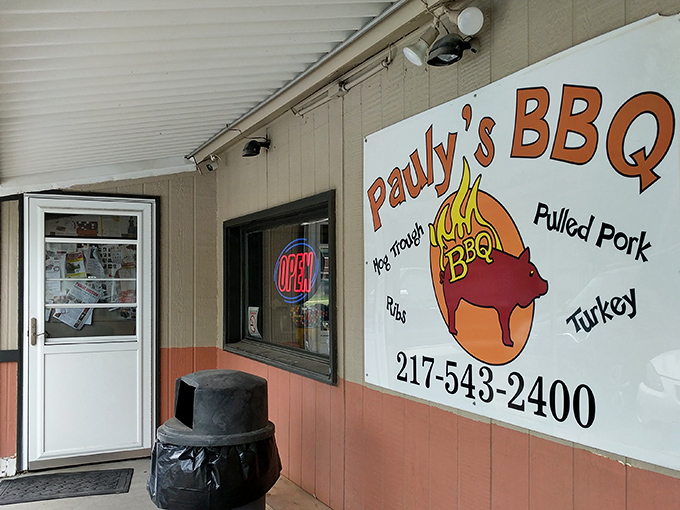 The welcoming entrance to Pauly's BBQ, where that neon "OPEN" sign might as well say "Happiness Served Here."