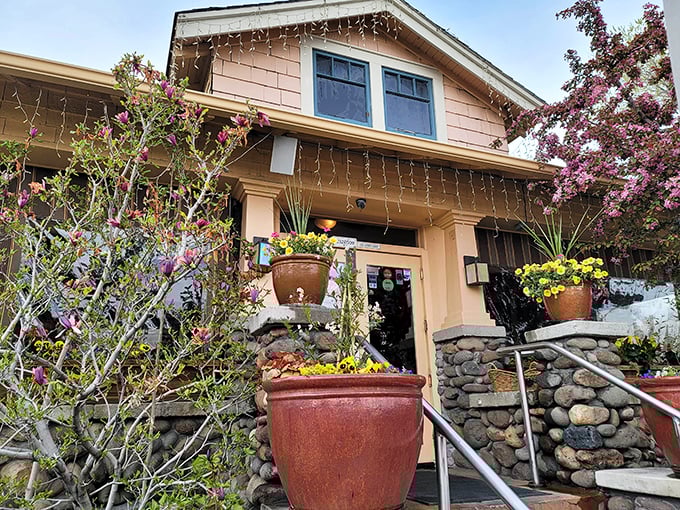 Spring blossoms frame this cozy caf&eacute;, where flowering trees and potted plants create a welcoming entrance that promises good things inside.