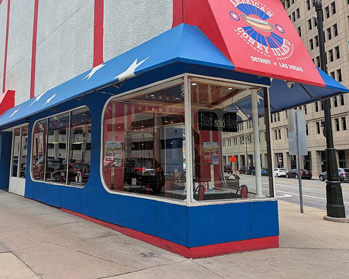 The patriotic awning of American Coney Island stands like a culinary lighthouse in downtown Detroit, beckoning hungry visitors with its red, white, and blue promise.