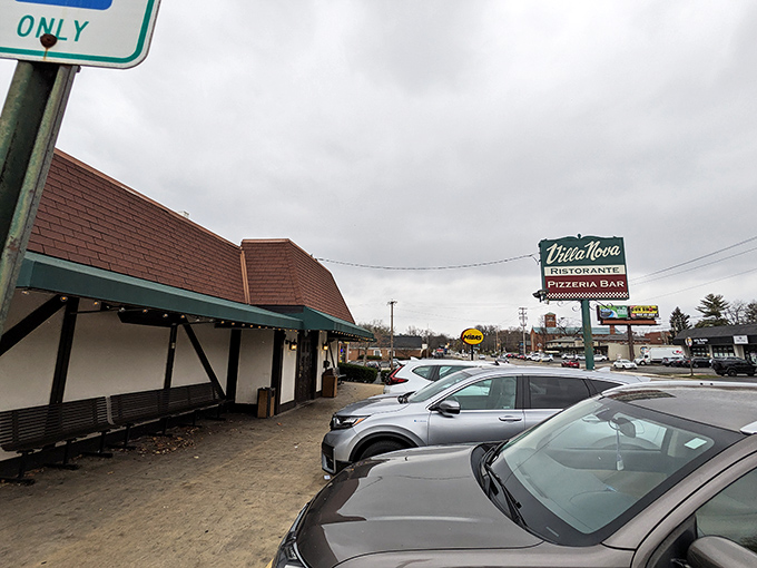 The A-frame entrance of Villa Nova stands like a culinary time capsule, its teal awning and vintage sign promising Italian comfort in Columbus's bustling landscape.