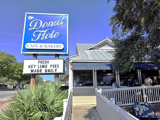 Morning sunshine illuminates the Donut Hole's welcoming facade. The white railing and blue awnings say "coastal charm" before you even taste a bite.