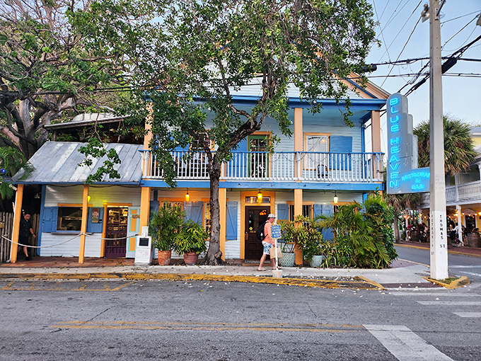 The iconic blue facade of Blue Heaven stands like a tropical mirage on a Key West corner, promising culinary adventures under the shade of sprawling trees.