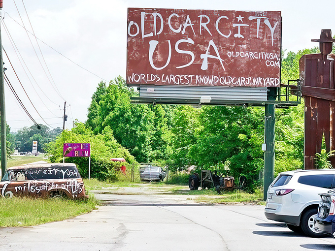 The weathered entrance sign promises adventure ahead. Nature and nostalgia collide at Old Car City USA, where rust becomes art and memories linger like Georgia humidity.