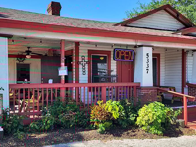 Old Florida charm greets you at this unassuming cottage with its red-trimmed porch and lush greenery. The neon "OPEN" sign beckons like an old friend.
