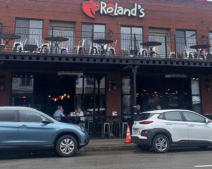 The brick facade of Roland's welcomes seafood pilgrims with its cheerful lobster mascot, promising maritime delights in Pittsburgh's historic Strip District.