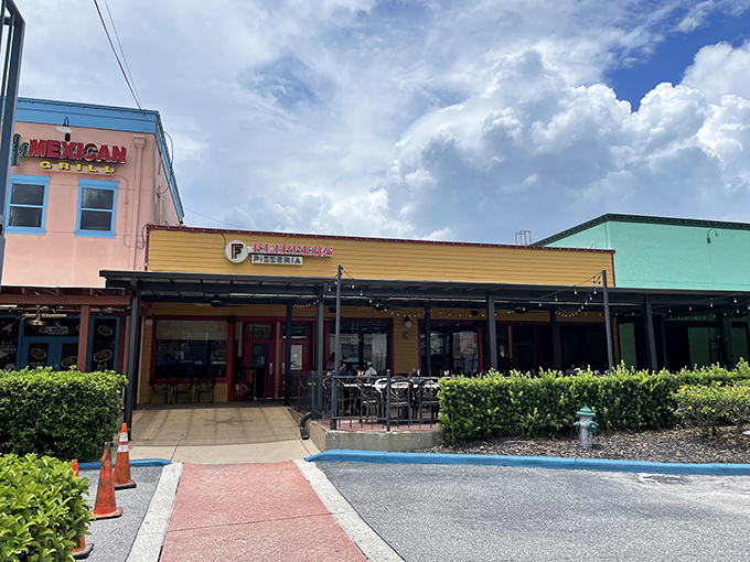 The cheerful yellow storefront of Flippers Pizza stands out in Old Town Kissimmee like a beacon for pizza pilgrims seeking salvation from theme park food.