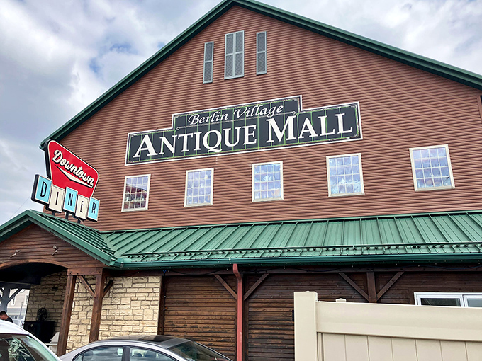 The iconic red barn exterior of Berlin Village Antique Mall stands as a beacon for treasure hunters, complete with that charming Downtown Diner sign promising sustenance after antiquing adventures.