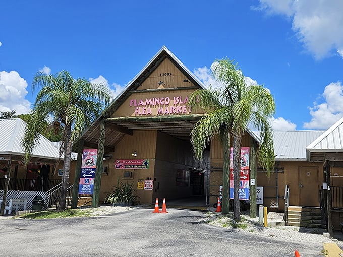 The rustic wooden entrance to Flamingo Island Flea Market stands like a portal to treasure-hunting paradise, framed by swaying Florida palms.