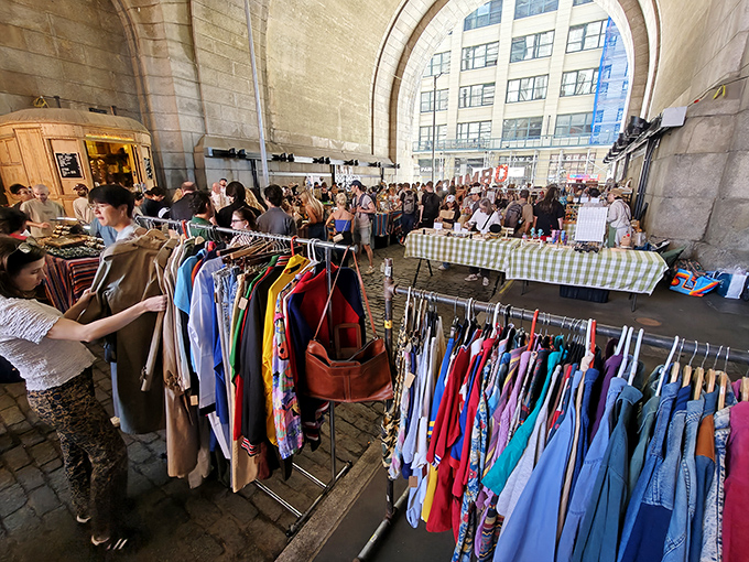 The majestic archway of DUMBO transforms into a treasure hunter's paradise, where Brooklyn Flea vendors create a magical marketplace beneath historic stonework.
