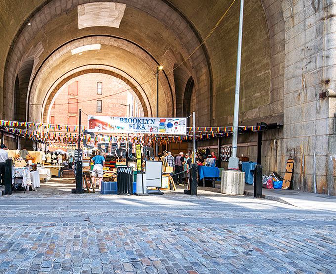 The majestic archway of DUMBO transforms into a treasure hunter's paradise, where Brooklyn Flea vendors create a magical marketplace beneath historic stonework.