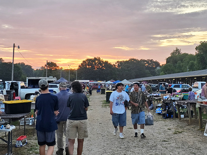 Dawn breaks over bargain paradise. The golden hour casts a magical glow on shoppers navigating the dusty pathways between vendors, each on their own quest for the perfect find.