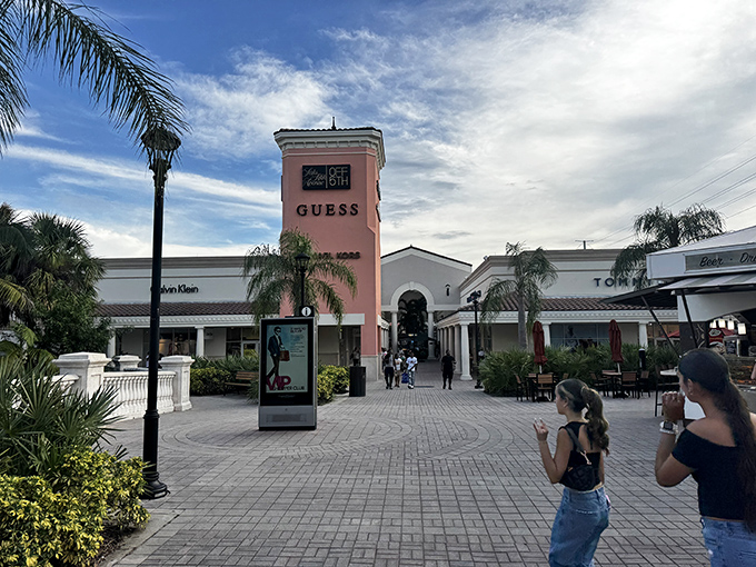 The iconic pink tower of the GUESS store stands like a fashionable lighthouse, guiding bargain hunters through a sea of designer deals.