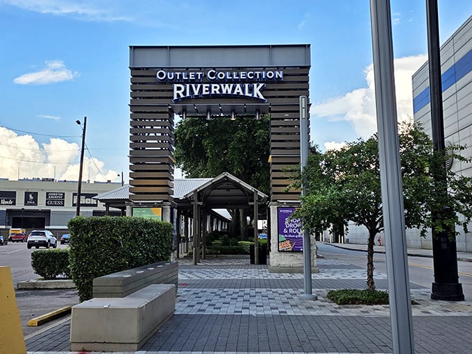 The bold blue lettering of Riverwalk stands out against the New Orleans skyline, offering retail therapy with scenic Mississippi River views.
