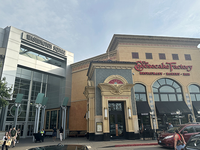 The grand entrance to Washington Square stands like a retail cathedral, with The Cheesecake Factory's golden fa&ccedil;ade promising indulgence before you've even stepped inside.