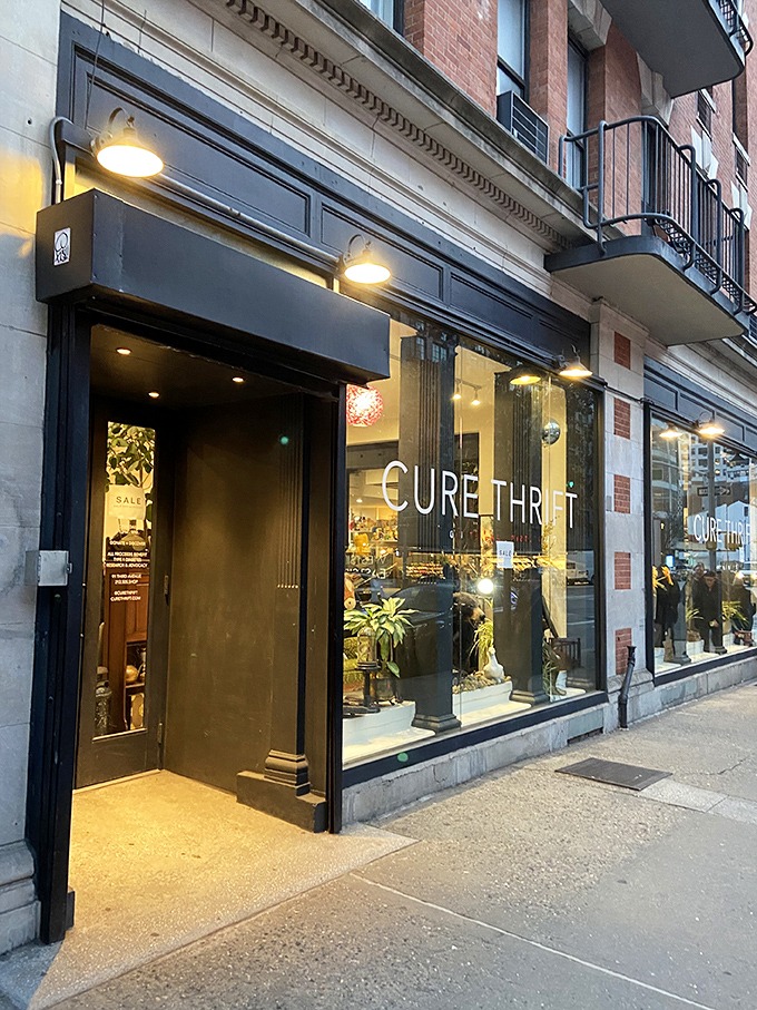 The sleek black exterior of Cure Thrift beckons passersby with its elegant signage and inviting window displays, promising treasures within.