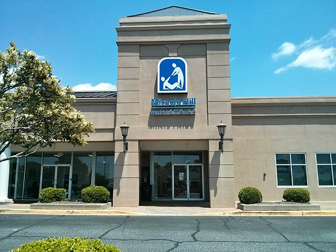 The welcoming entrance features the iconic blue Miracle Hill logo, where thrifting adventures begin and wallets breathe sighs of relief.