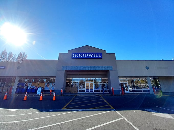 The blue Goodwill sign beckons like a lighthouse to bargain hunters. Under clear Washington skies, this unassuming exterior houses countless treasures waiting to be discovered.