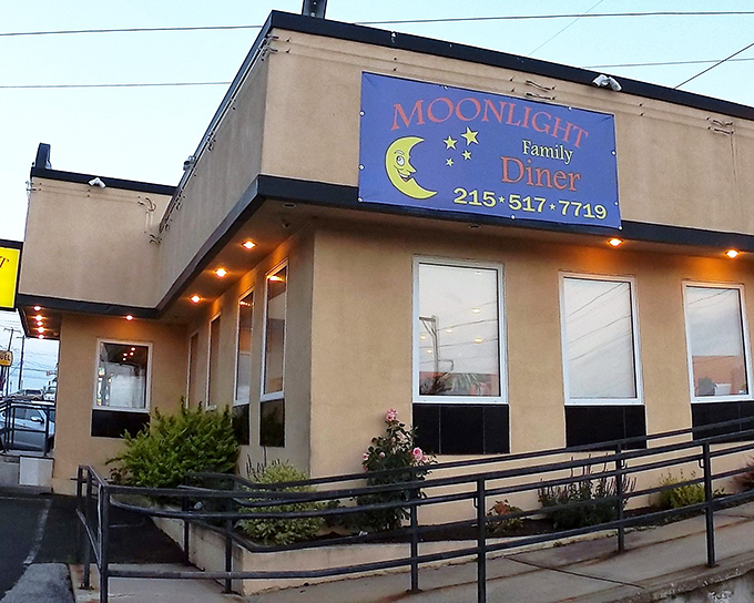 The iconic blue sign of Moonlight Diner glows with promise against the tan exterior&mdash;a beacon of comfort food in Glenside's landscape.