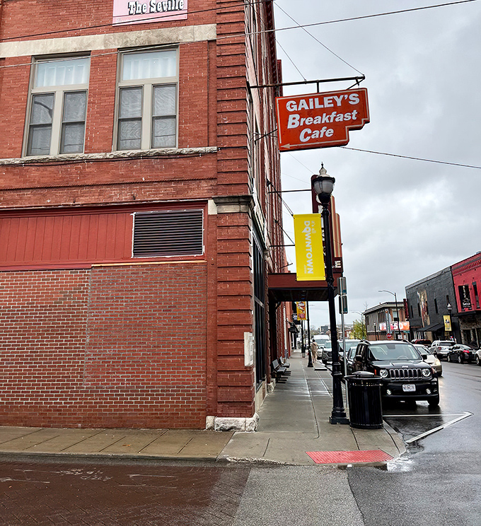 That cheerful red sign on the historic brick building promises breakfast excellence, and spoiler alert: it delivers every single time.