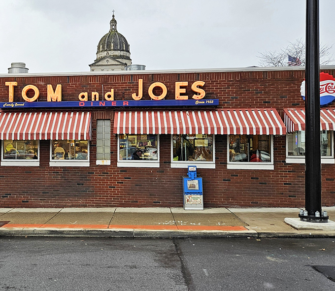 The classic red brick exterior of Tom & Joe's stands as a beacon of breakfast hope against the Altoona skyline, those striped awnings practically waving you inside.