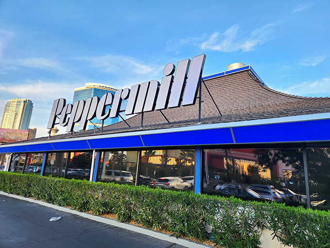 Sunset casts a golden glow on Peppermill's distinctive blue-trimmed exterior, a mid-century modern masterpiece that's outlasted countless Vegas reinventions.