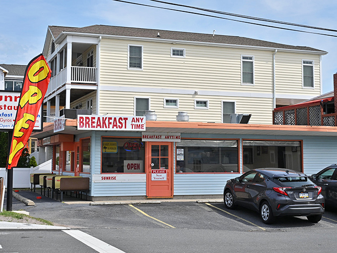 The bright orange door and "BREAKFAST ANY TIME" sign are like culinary bat signals to hungry beachgoers. No cape required, just an appetite.