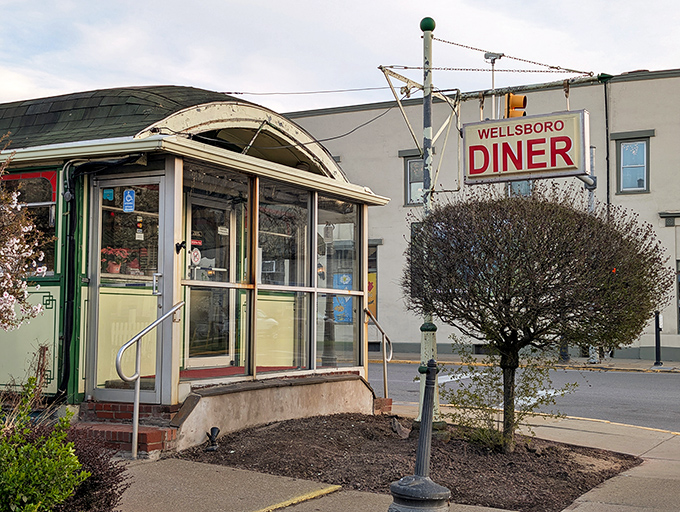 The iconic Wellsboro Diner exterior stands like a time capsule on Main Street, its vintage sign promising authentic comfort food without pretense.