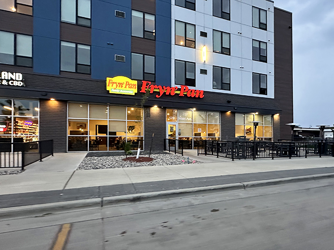 The bright red Fryn' Pan sign glows like a beacon of comfort food against Fargo's modern architecture. Dinner salvation awaits inside!