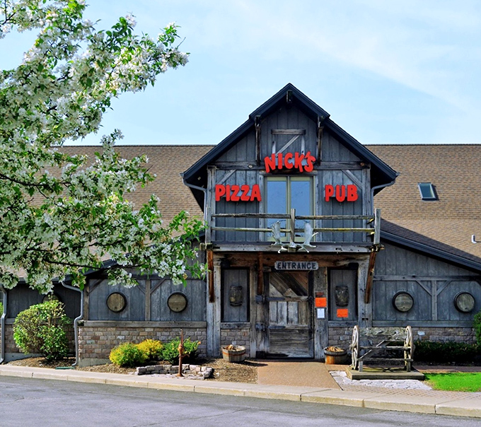 The rustic log cabin exterior of Nick's Pizza & Pub looks like Paul Bunyan's dream retirement home, complete with weathered wood charm and inviting front porch.