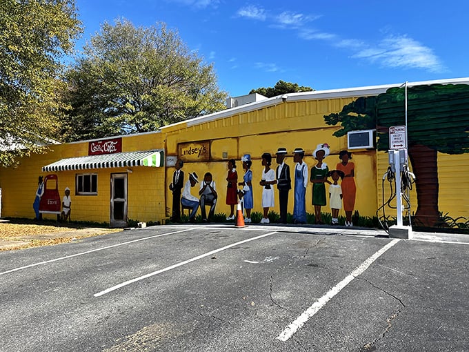 The sunshine-yellow exterior of Lindsey's Hospitality House stands out like a beacon of BBQ hope, with its vibrant mural celebrating community and culture.