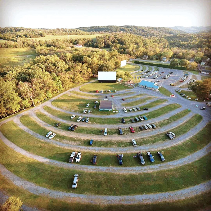 The perfect amphitheater for cinematic magic—concentric rings of cars facing a glowing screen against Pennsylvania's rolling hills at dusk.