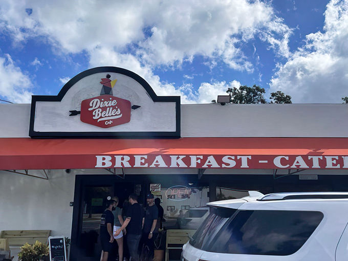 Morning sunshine illuminates Dixie Belle's welcoming facade, where staff members gather by the entrance, ready to usher in hungry patrons seeking Southern breakfast bliss.
