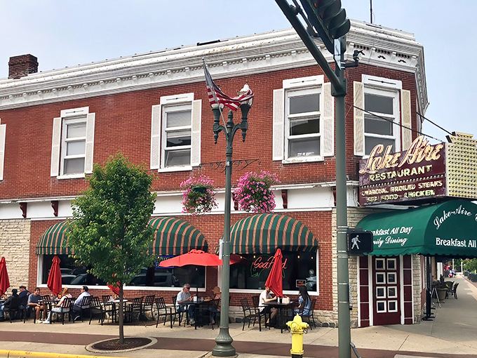 The iconic red brick exterior of Lake Aire Restaurant stands as a beacon of breakfast hope on Lake Geneva's bustling corner, complete with those inviting green awnings.
