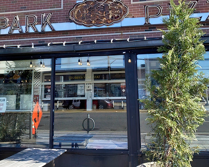 The iconic neon sign of New Park Pizza beckons hungry travelers like a lighthouse guiding ships to safe harbor. Pizza paradise awaits.