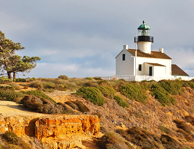 The Old Point Loma Lighthouse stands like a Victorian postcard against a cotton candy sky, its green-domed beacon a silent sentinel over San Diego's waters.