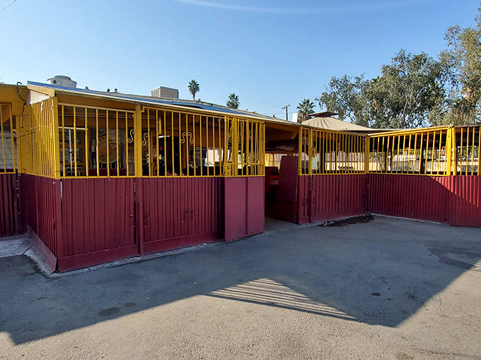 A welcoming outdoor seating area protected by the restaurant's signature burgundy and yellow fencing offers a casual spot to enjoy authentic Mexican cuisine.
