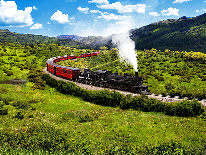 Nature's amphitheater unfolds as the crimson cars snake through verdant valleys. This isn't just transportation&mdash;it's time travel with panoramic views.