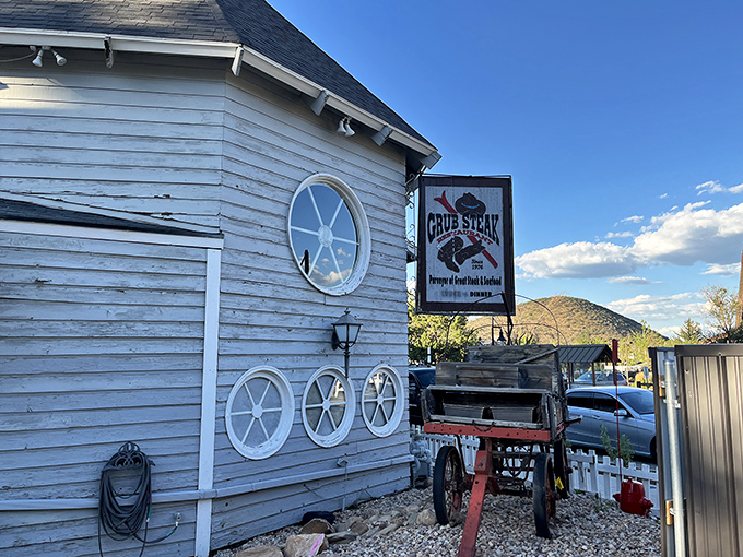 The weathered white clapboard exterior of Grub Steak whispers tales of countless memorable meals, while that vintage wagon stands guard like a time-traveling ma&icirc;tre d'.