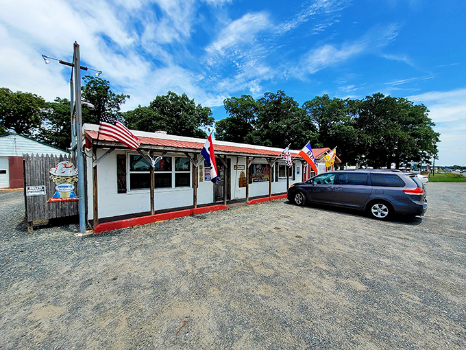 American flags flutter proudly outside this roadside gem, where the gravel parking lot serves as a prelude to the no-frills, all-flavor experience ahead.