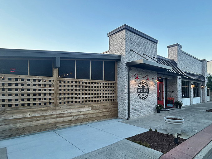 The unassuming brick exterior with that pop of red door is like a secret handshake &ndash; those who know, know this is where barbecue magic happens.