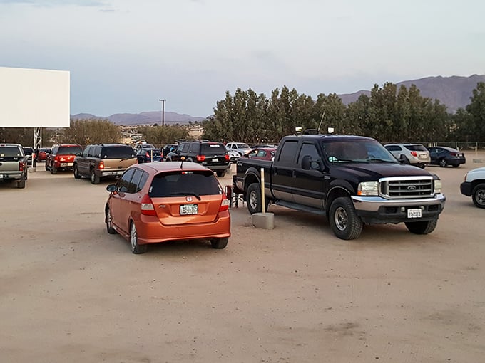 Cars lined up under the desert twilight, facing the blank canvas that will soon transport viewers to another world.