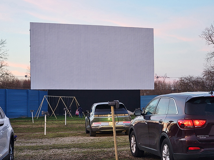 The iconic white screen of Blue Sky Drive-In stands ready for dusk, when movie magic transforms this simple structure into a portal to another era.