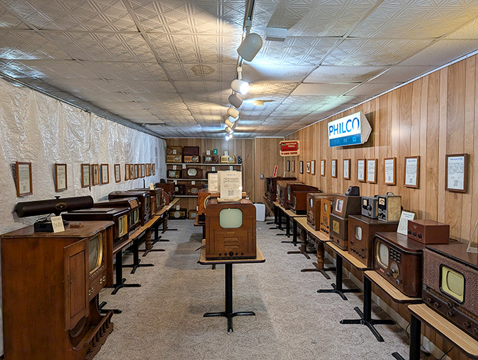 Rows of wooden consoles line this time capsule of television history, where vintage sets stand at attention like soldiers from a bygone electronic era.