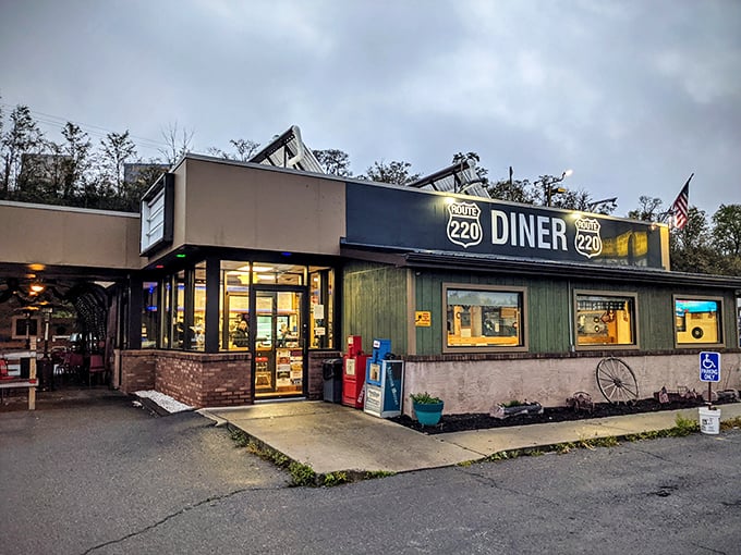 The cozy, no-frills exterior of Route 220 Diner glows warmly at dusk, inviting travelers in for hearty comfort food and hometown charm.
