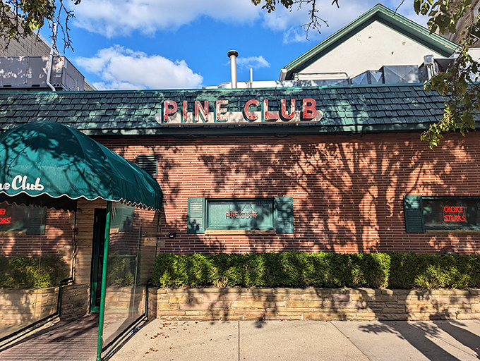 The iconic green awning and brick facade of Pine Club stand as a beacon for steak lovers, promising old-school excellence behind those unassuming doors.