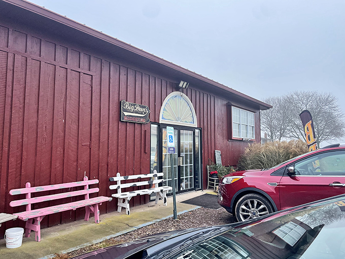 The red barn exterior of Big Dan's BBQ stands as a beacon of hope for hungry travelers. Those pink benches aren't just seating&mdash;they're waiting rooms for flavor paradise.